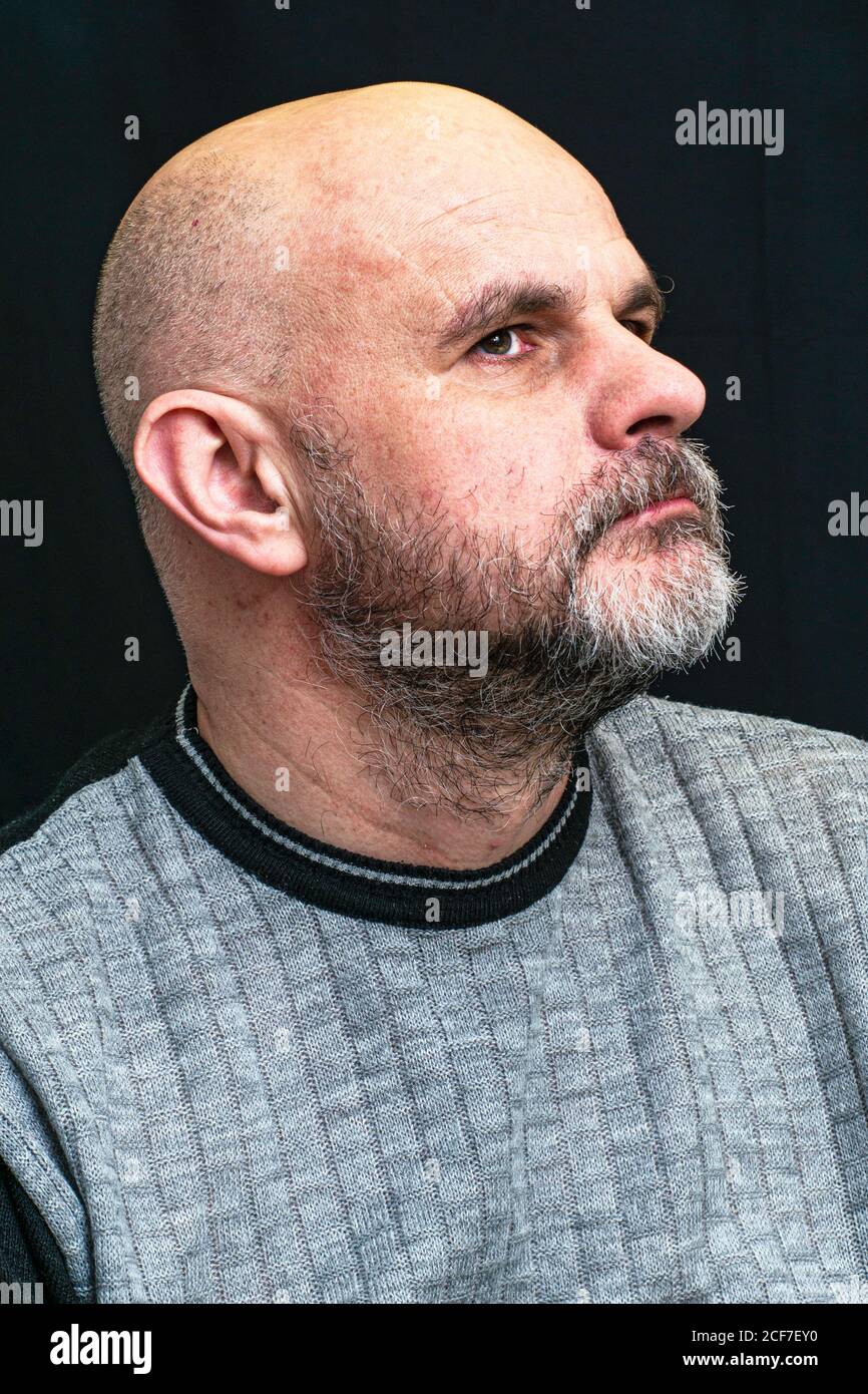 Portrait Of A Middle Aged Bald Bearded Man In Profile On A Black