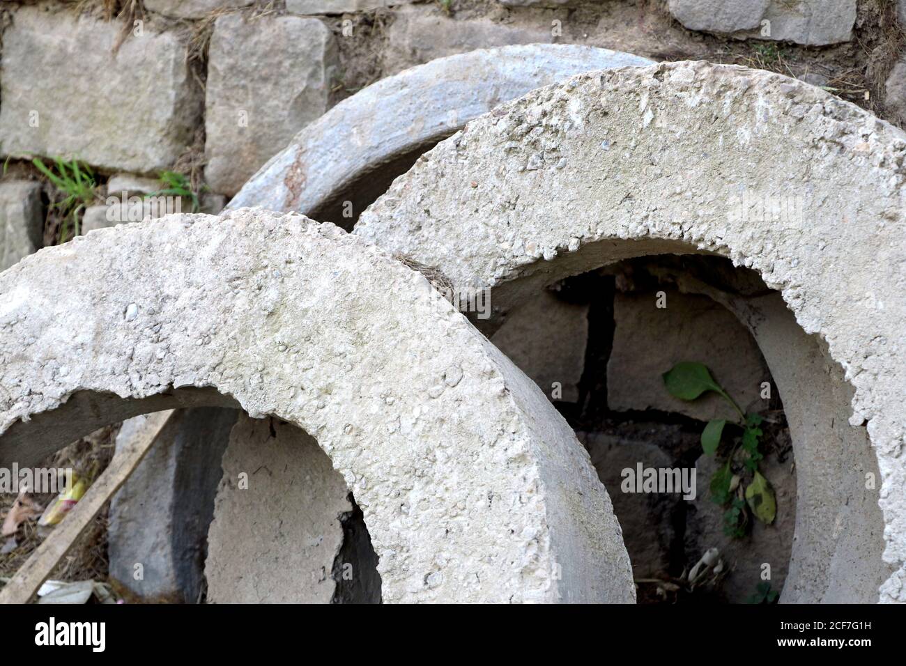 Closeup of large concrete rings leaning on the stone wall during ...