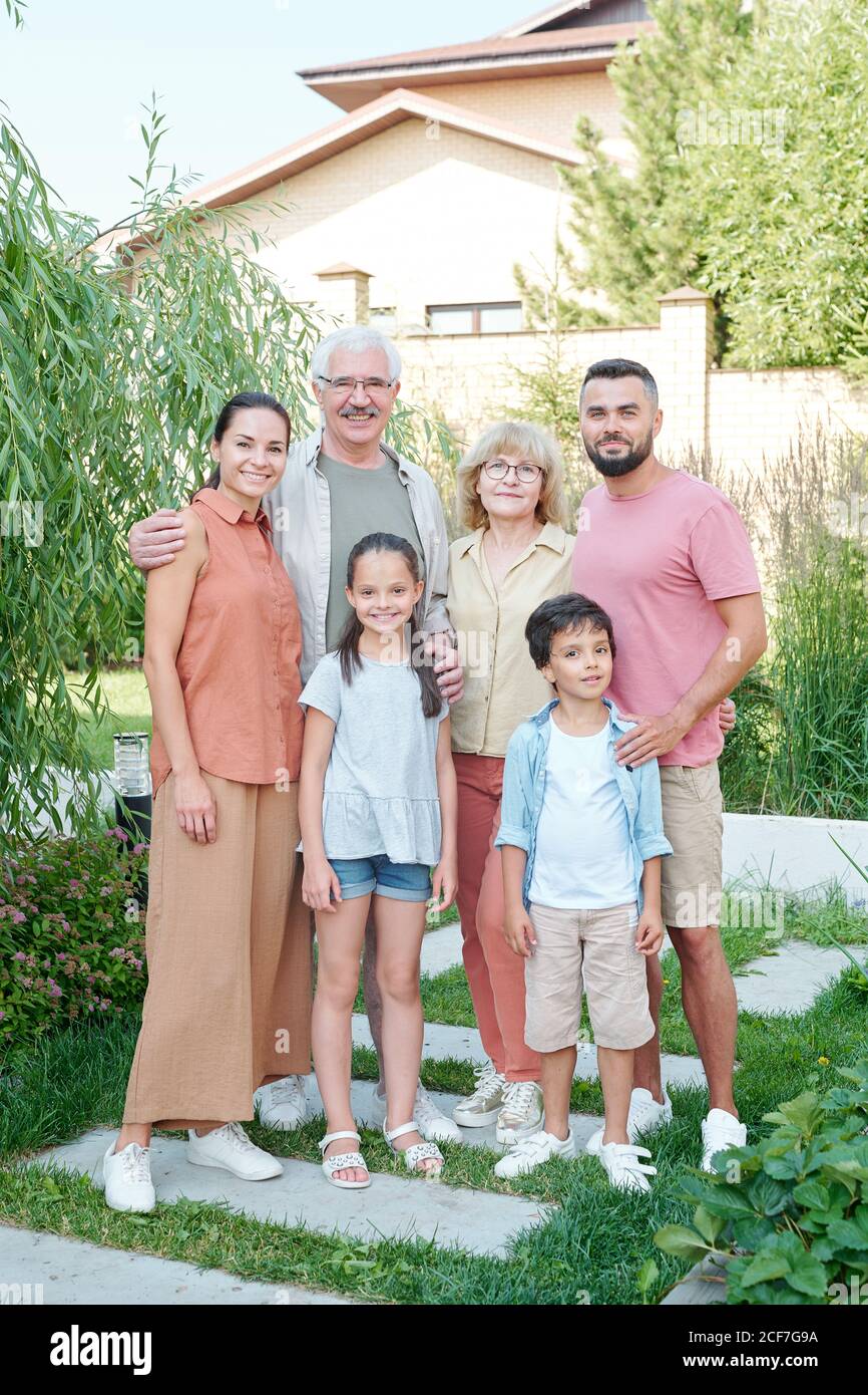 Vertical full shot portrait of multi-generation family of six standing ...
