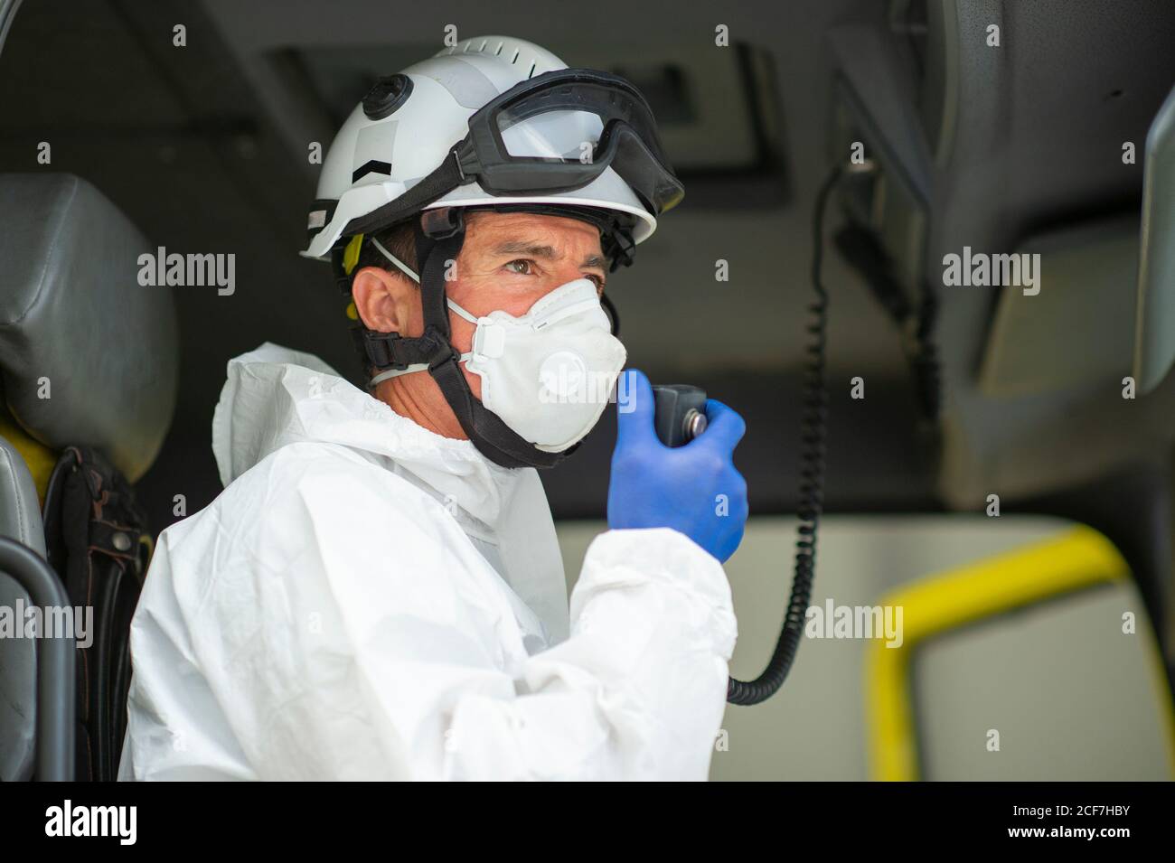 Side view firefighter wearing respirator and helmet sitting in fire car ...