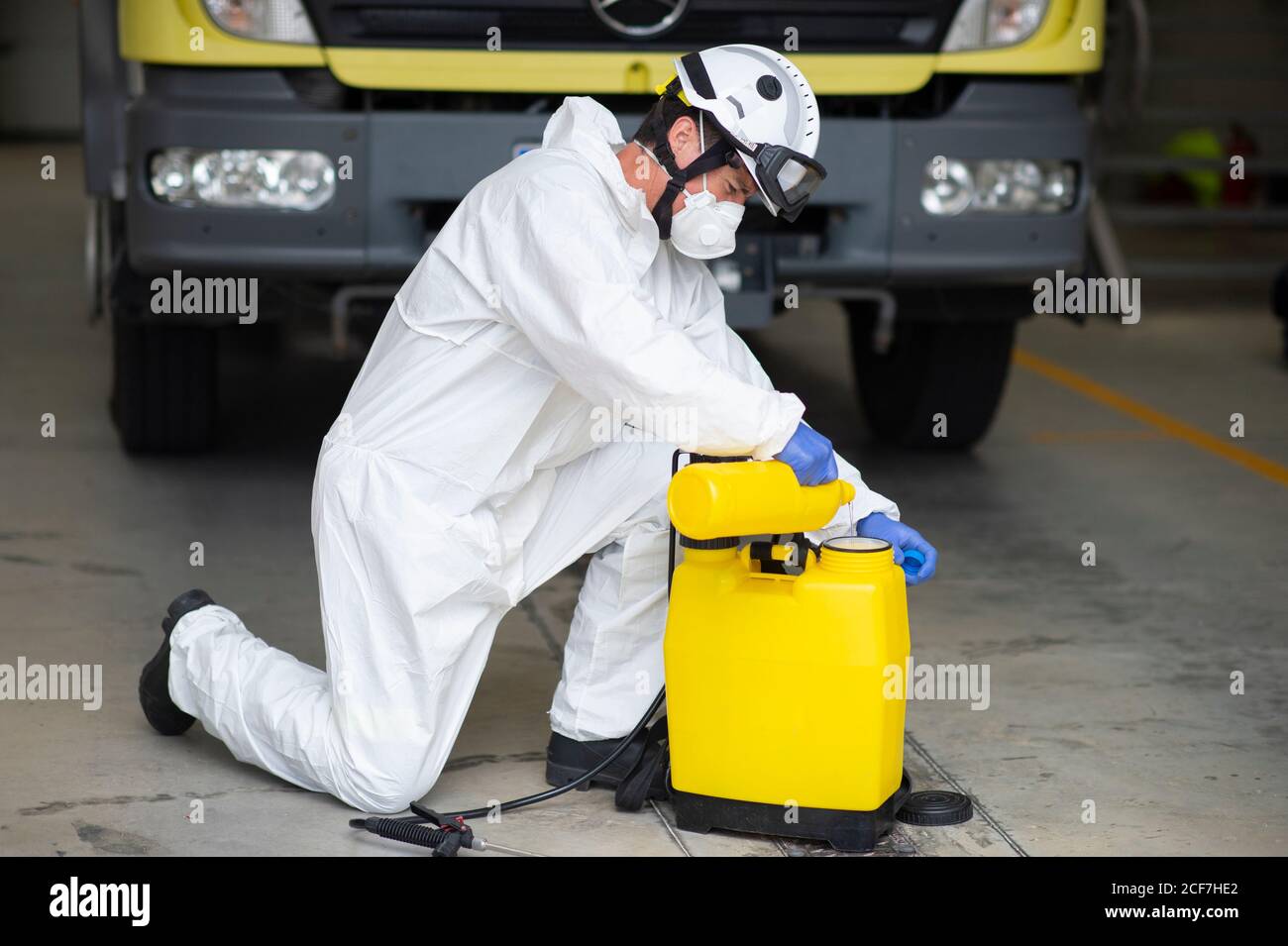 Side view of fireman in protective costume and respirator pouring ...