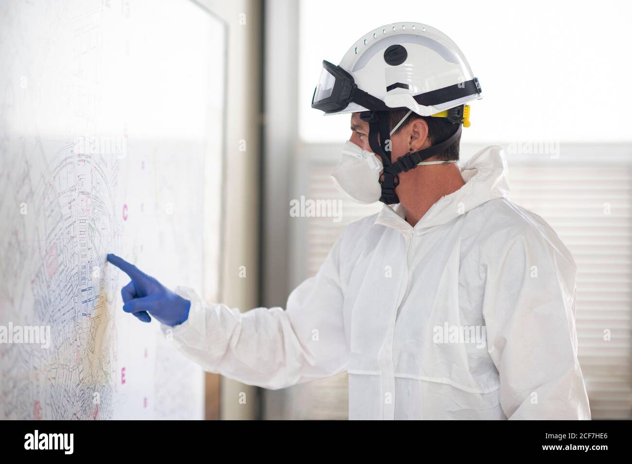 Side view of fireman wearing protective costume and respirator standing ...