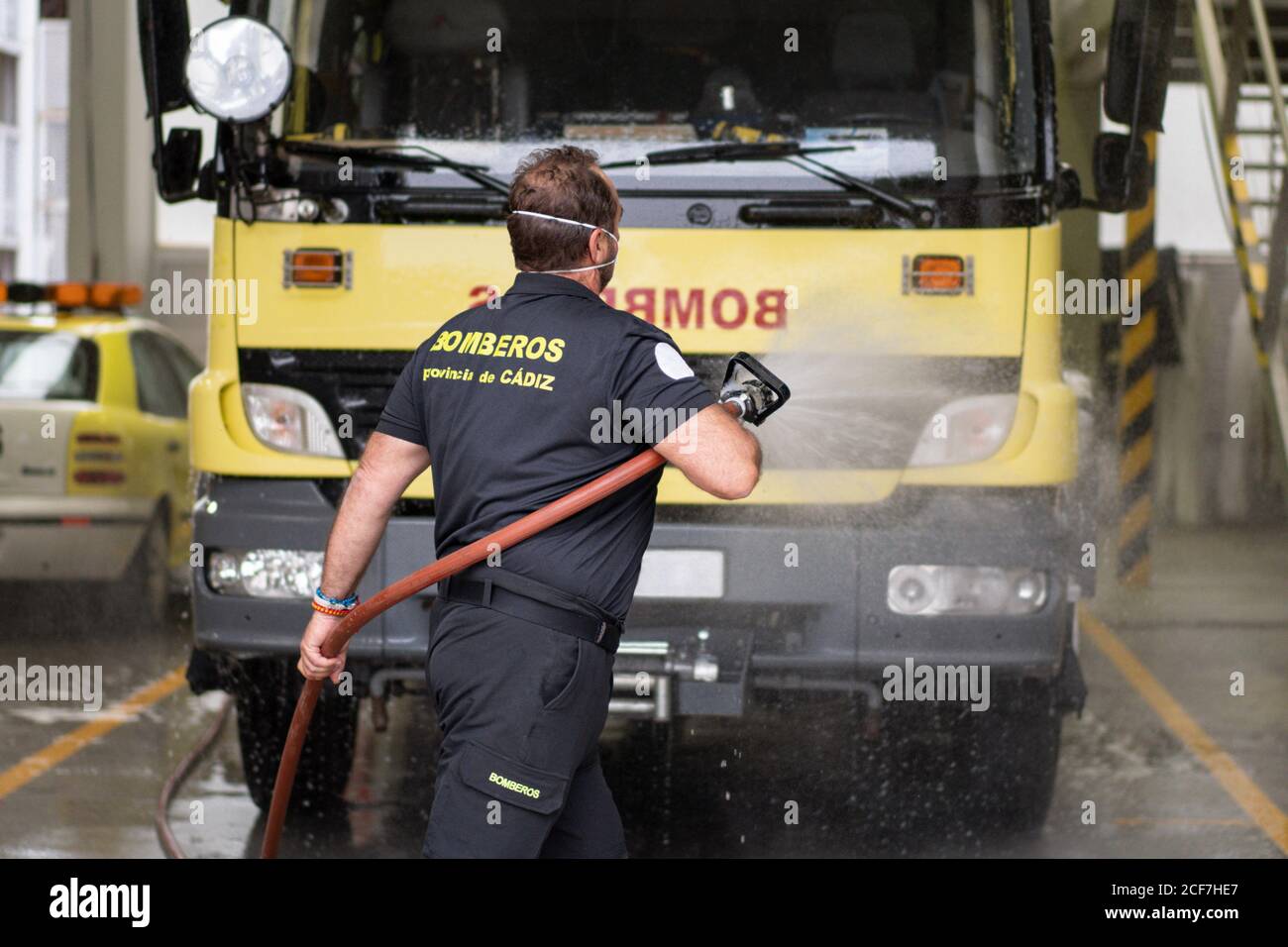 Back view of firefighter washing car with fire hose at station Stock ...