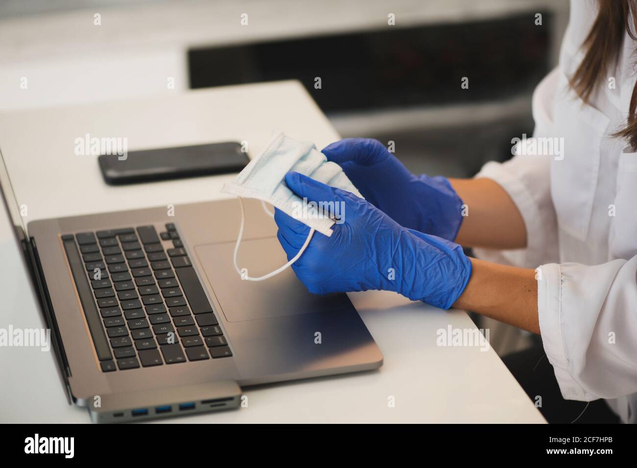 Crop anonymous female in latex gloves holding medical protective face ...