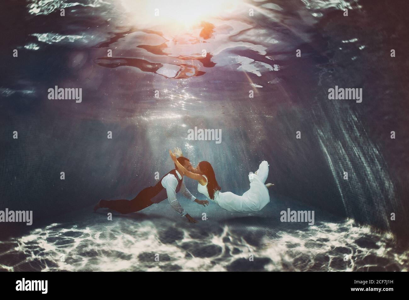 Side view of happy romantic couple swimming together underwater in ...