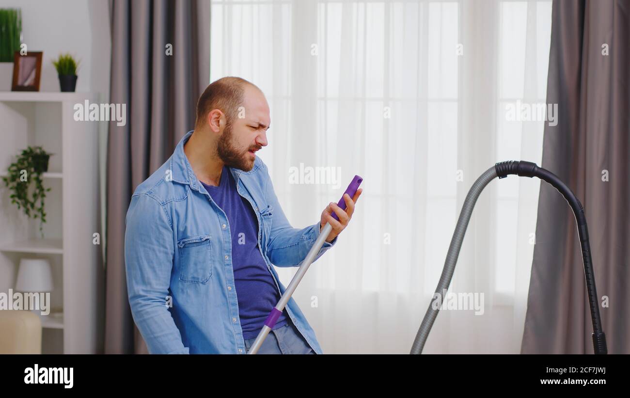 Cheerful man singing on mop and cleaning his room Stock Photo - Alamy