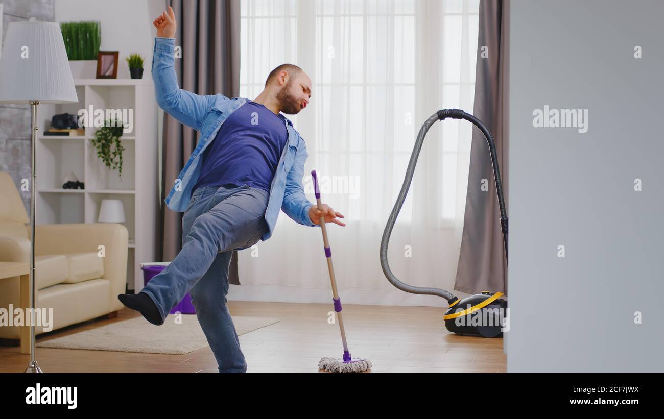 Excited young man dancing while cleaning his apartment Stock Photo - Alamy