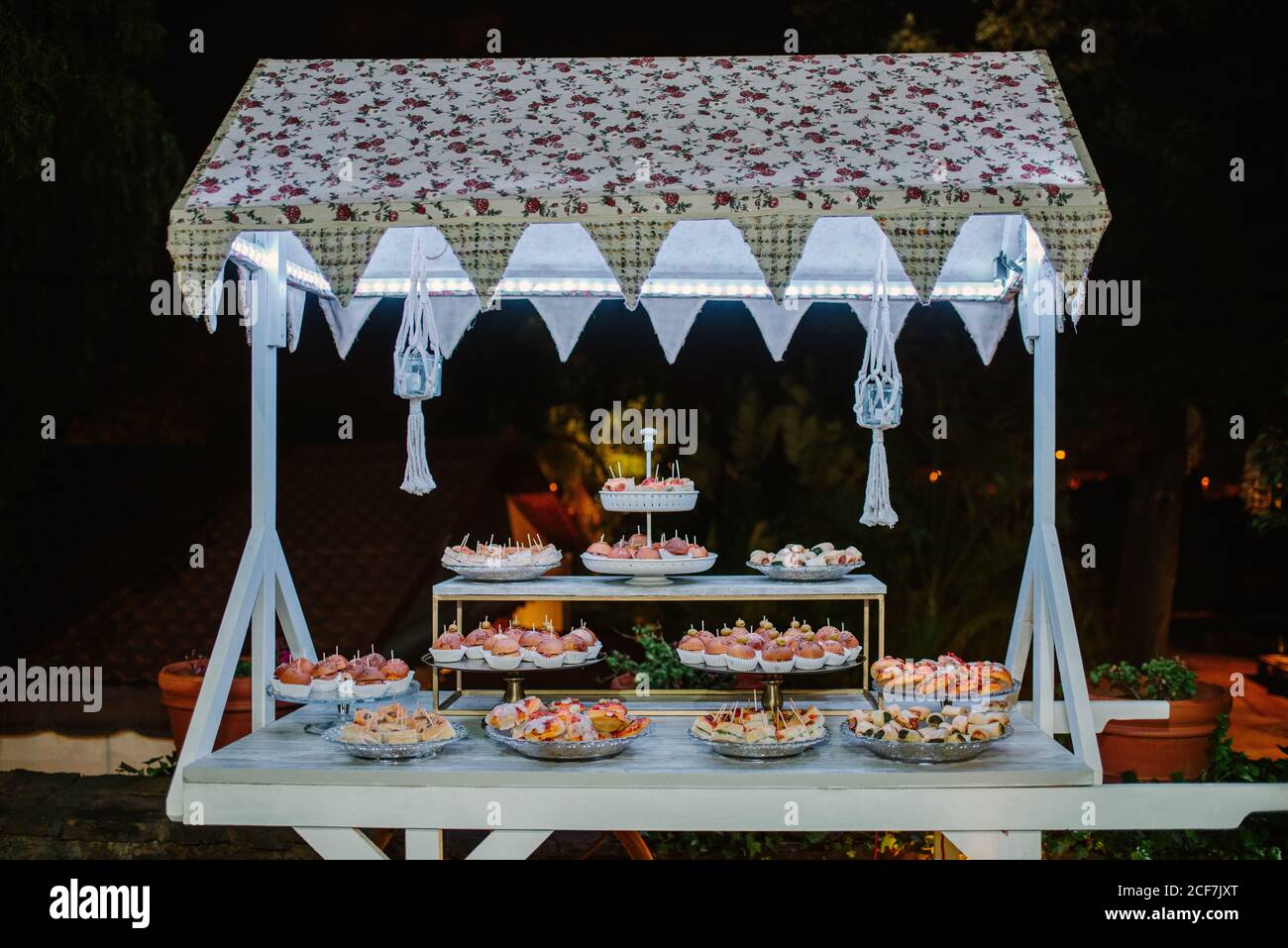 Plates of tasty canapes placed on illuminated counter in dark courtyard ...