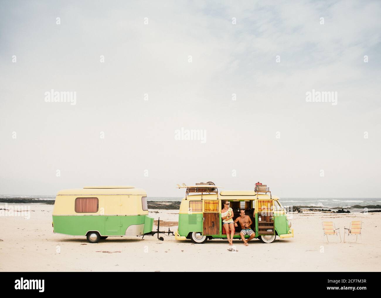 Side view of retro vehicle with trailer and friends sitting in car on ...