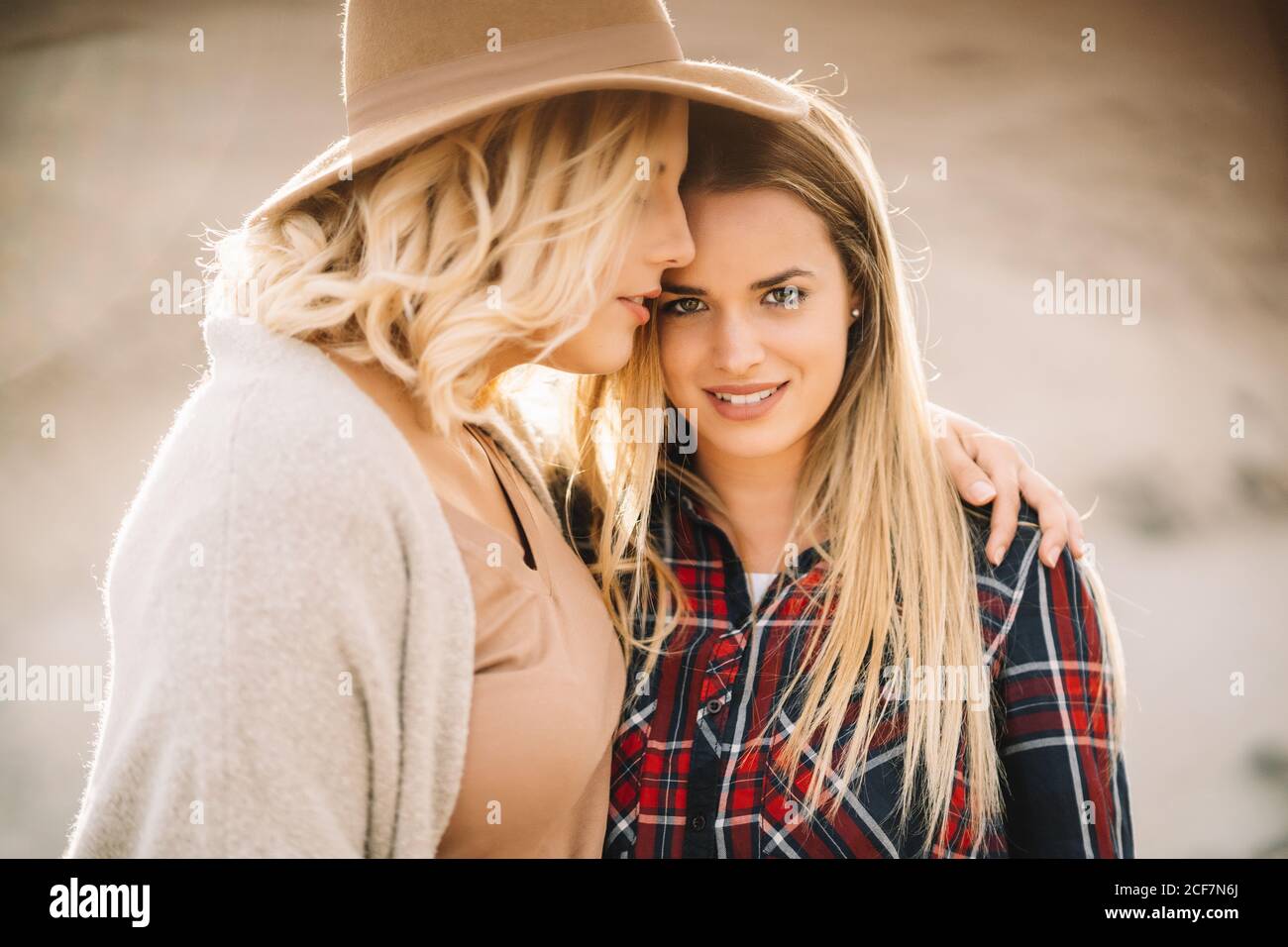 Woman in hat wearing casual clothes tenderly hugging female with long ...