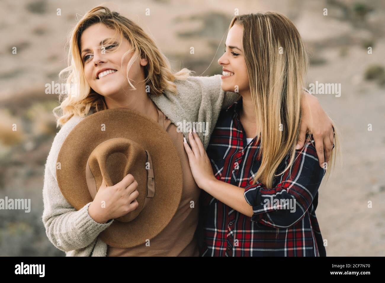 Woman in hat wearing casual clothes tenderly hugging female with long ...