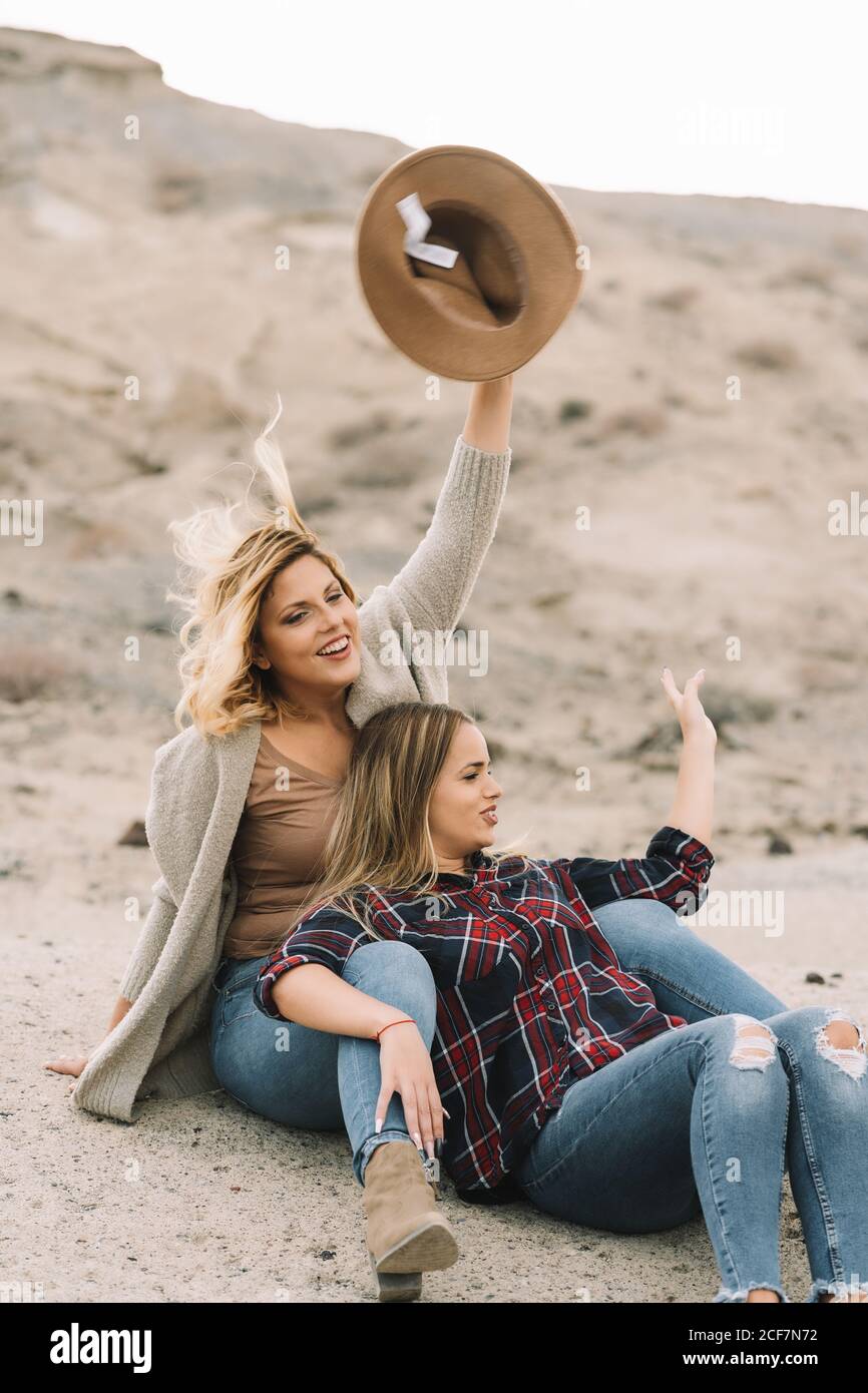 Woman holding hat wearing casual clothes tenderly hugging female with ...