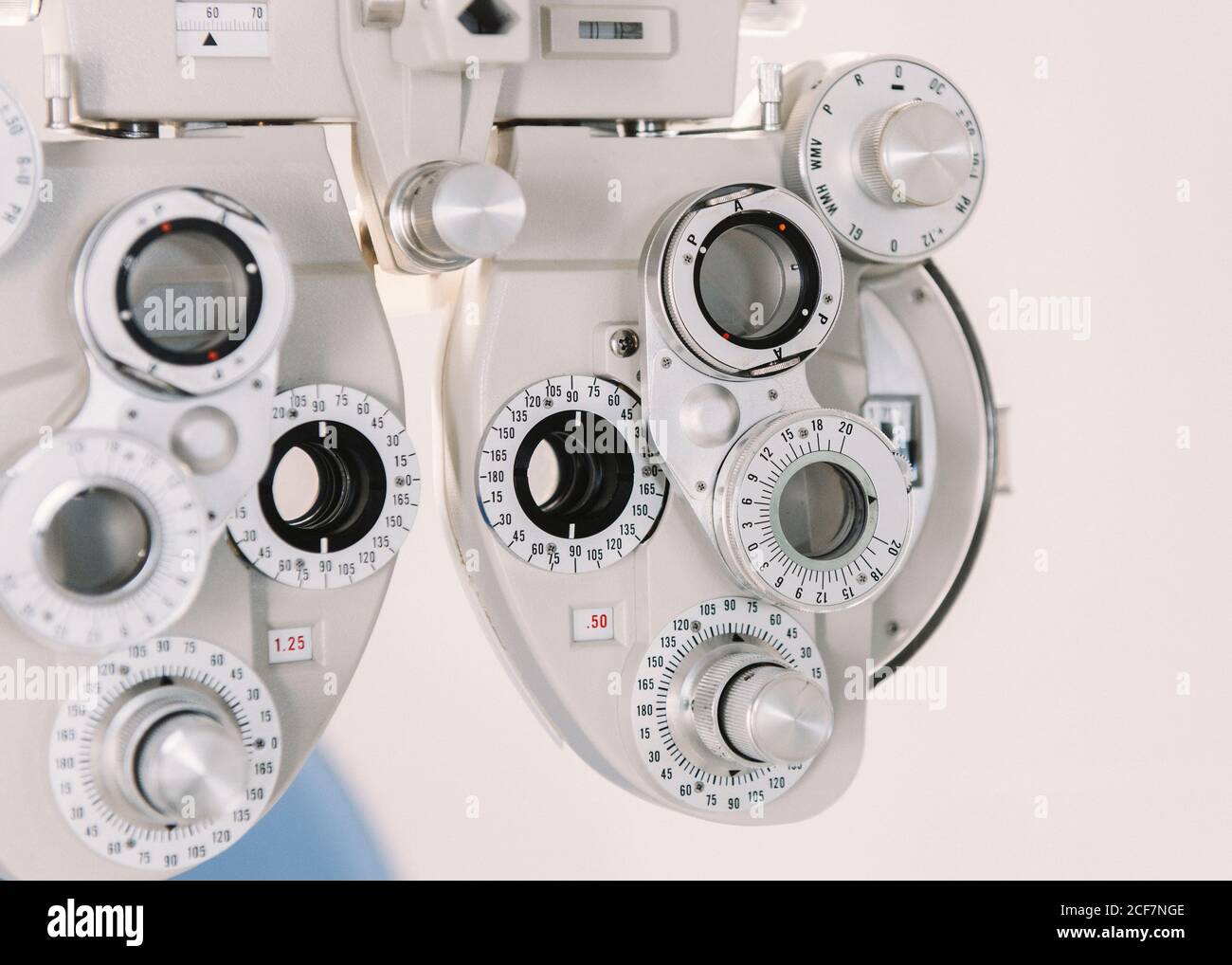 Modern vision test equipment and chair against white wall in optician ...