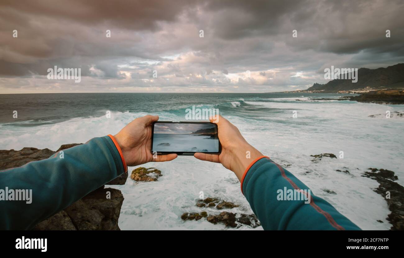 First person view of a man taking a picture with phone at a seashore ...