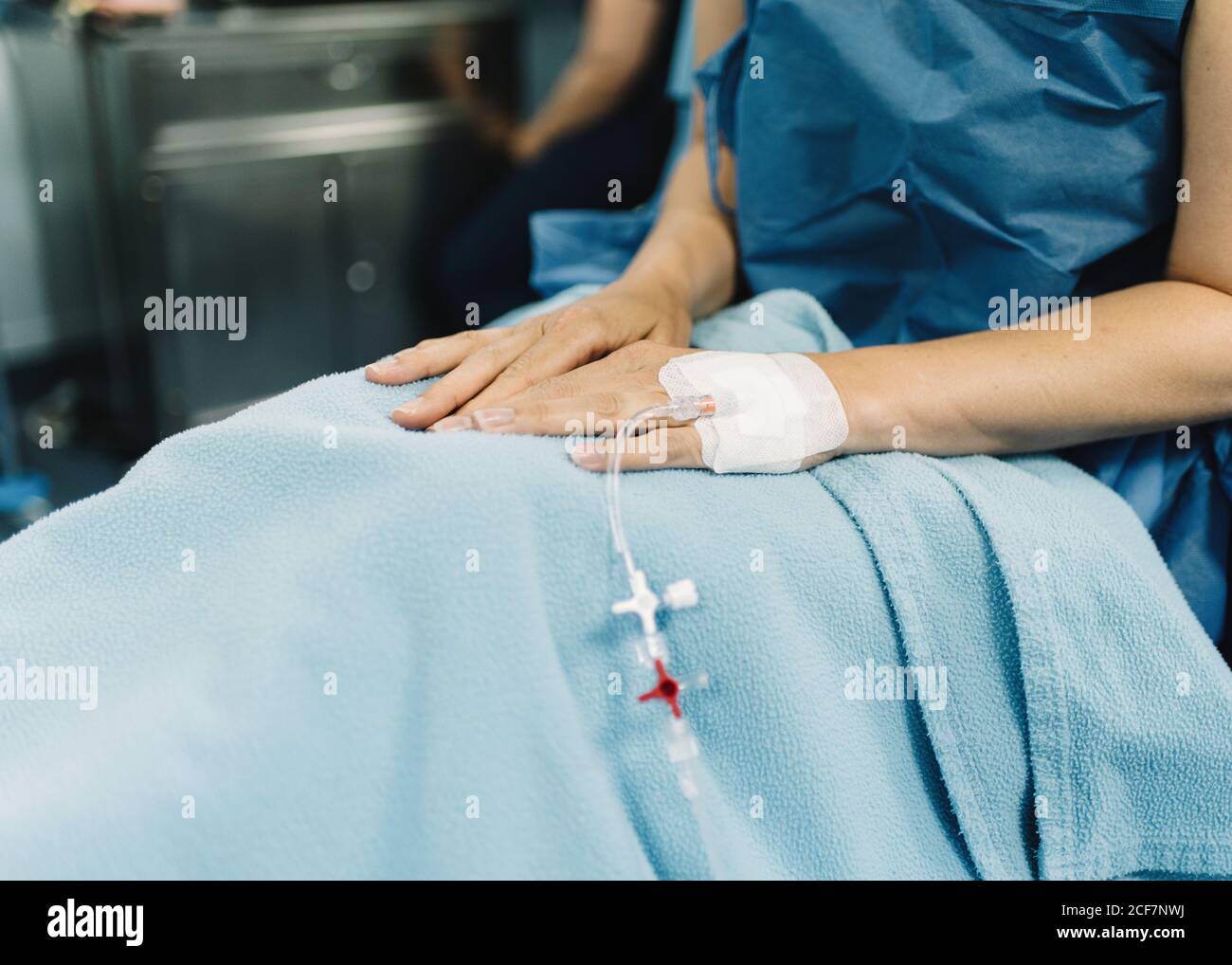 Crop female patient sitting with covered legs and intravenous fluid ...