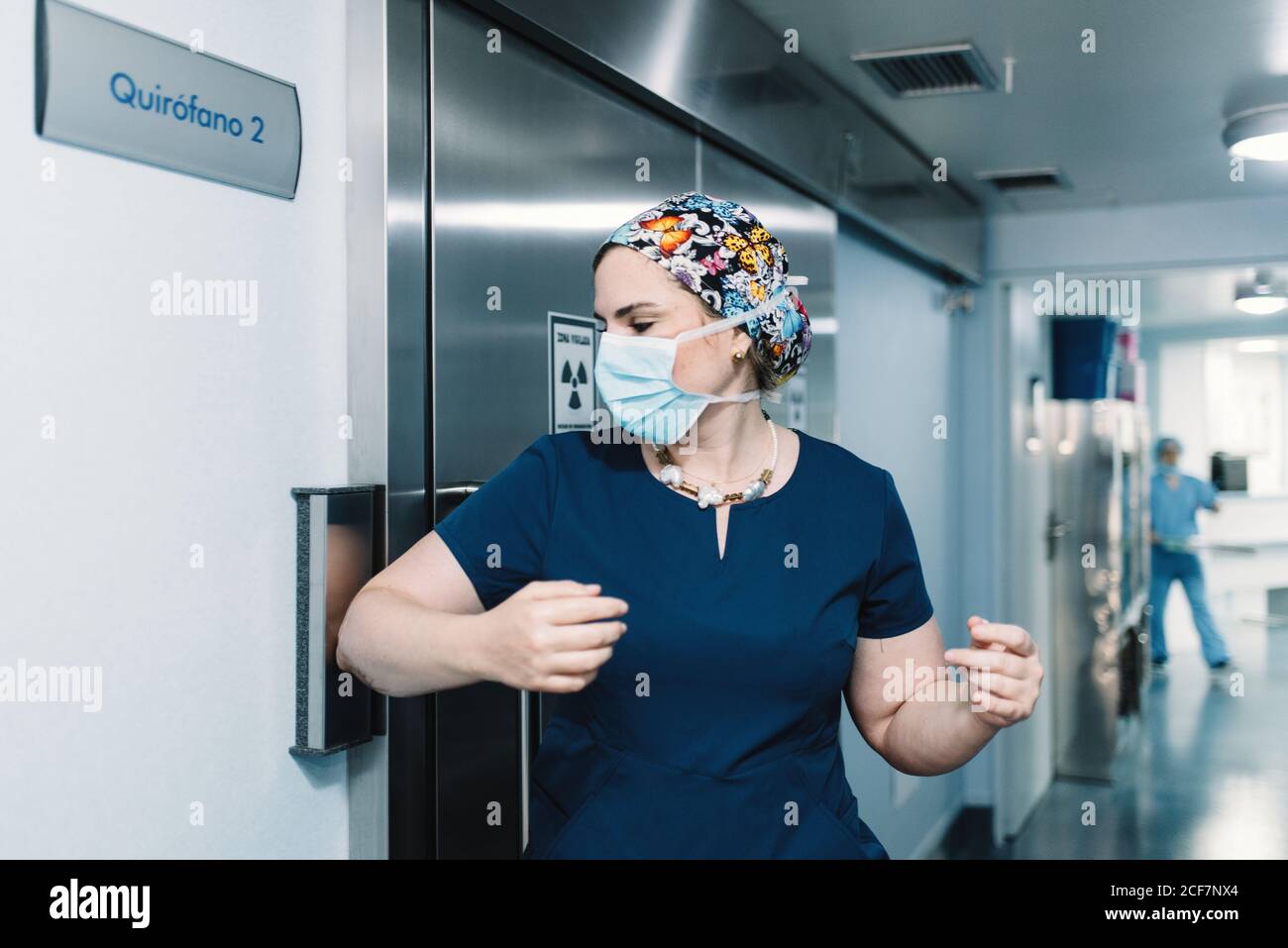Side view of Woman in blue uniform and protective mask coming in ...
