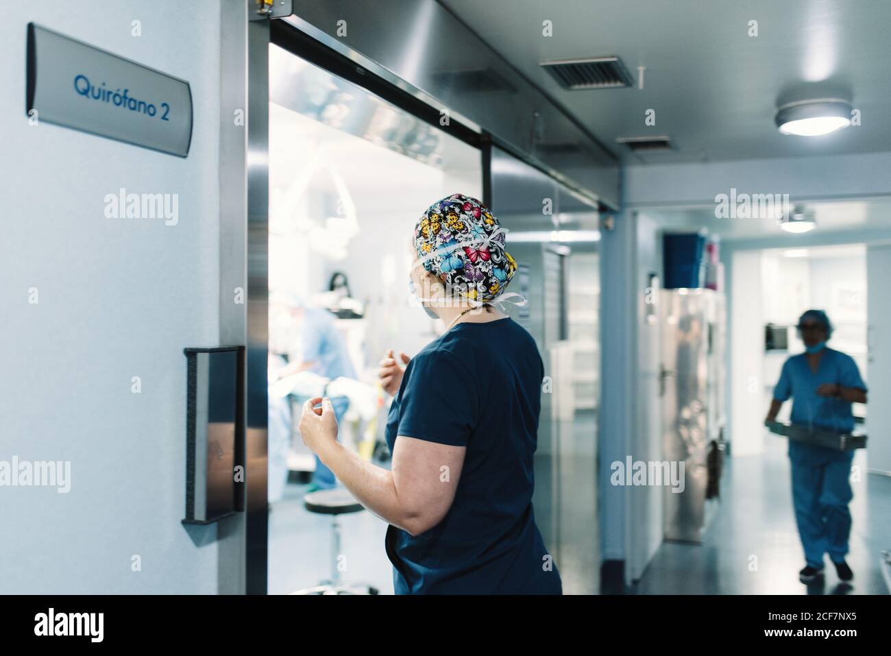 Side view of Woman in blue uniform and protective mask coming in ...