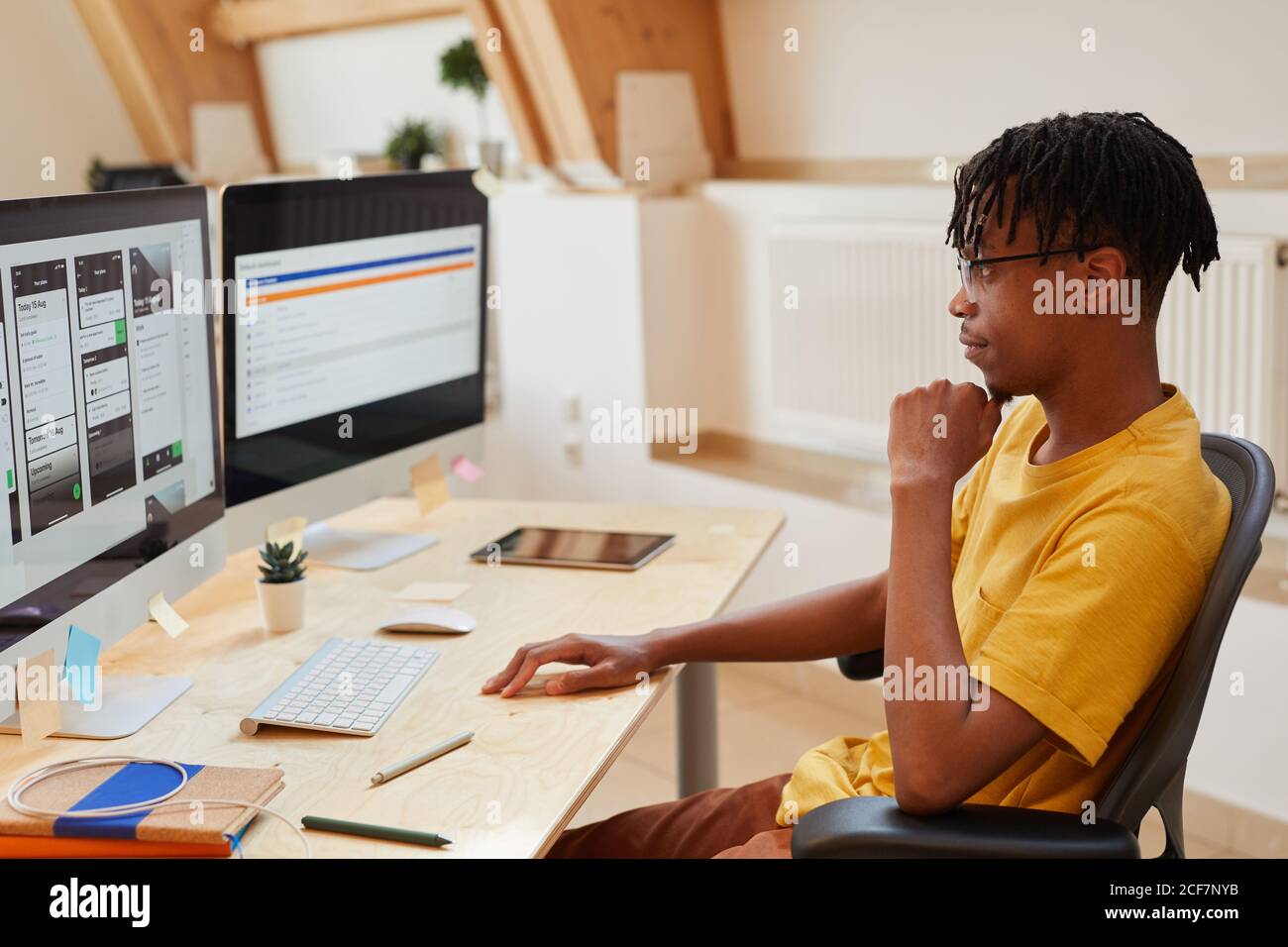 African developer sitting at the table in front of computer monitors he ...