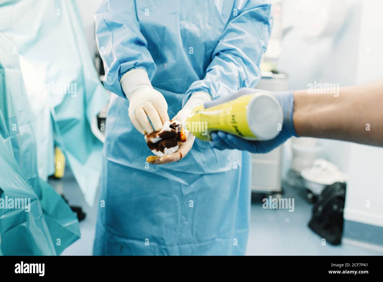 Crop hands of medic pouring iodine to tampon for disinfecting patient ...