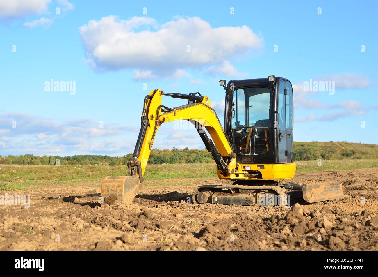 Mini excavator digging earth in a field or forest. Laying underground ...