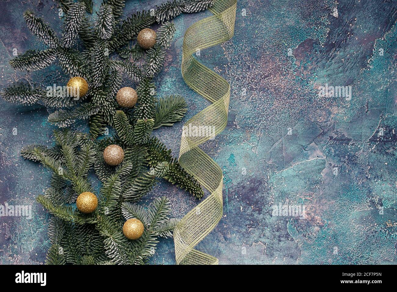 Border of green spruce branches with Christmas decorations on a gray ...