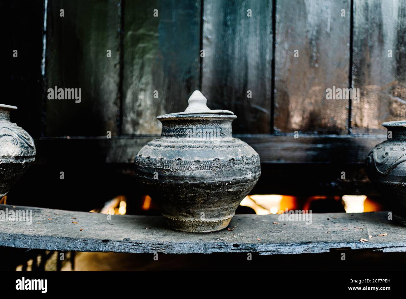 Old gray stone jug with lid located on wooden shelf against wall in ...