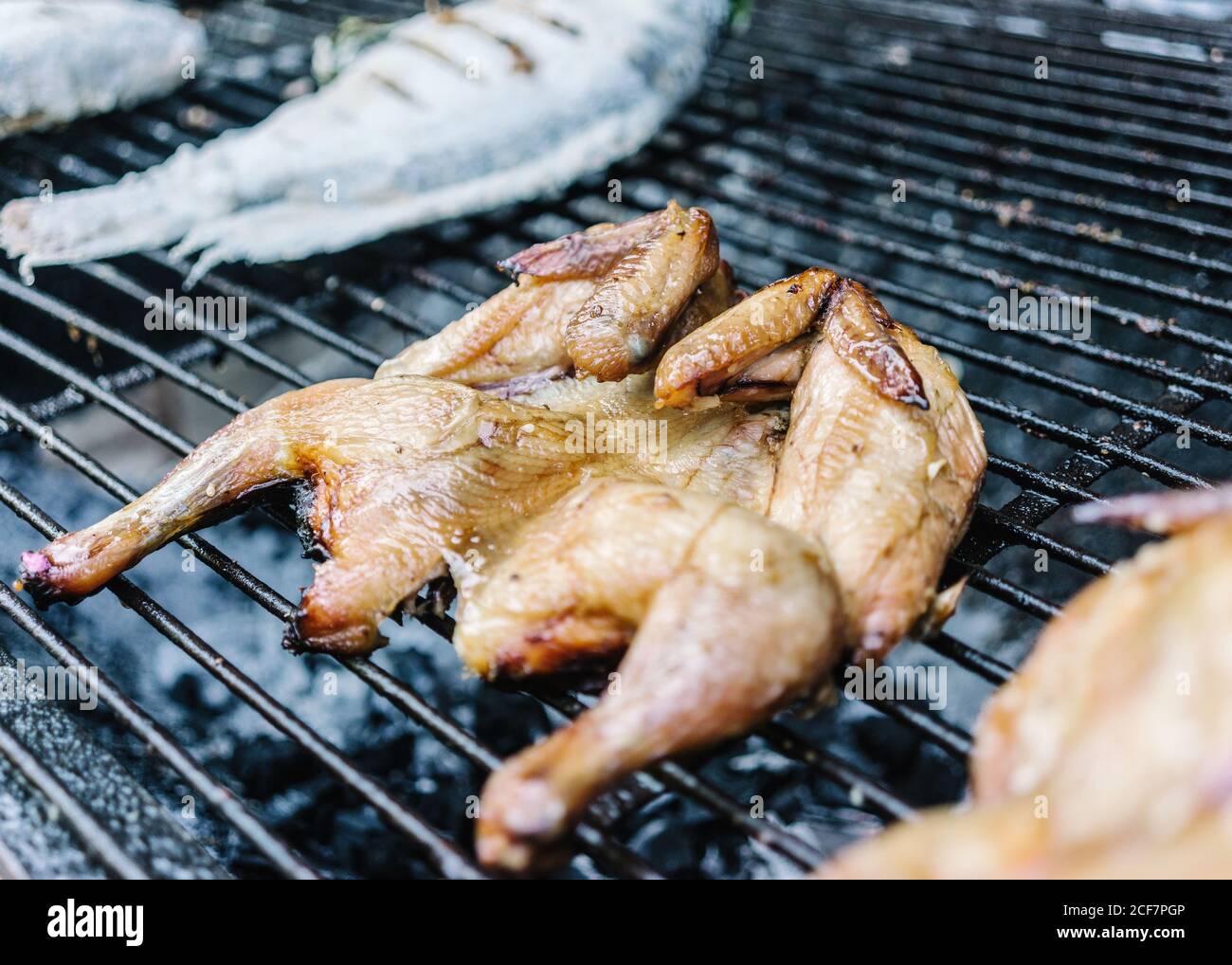 From above of big golden chicken and fish on metal grill in restaurant ...