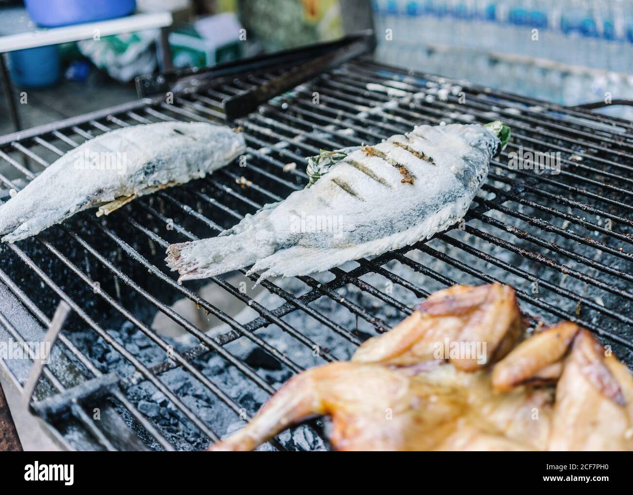 From above of big golden chicken and fish on metal grill in restaurant ...