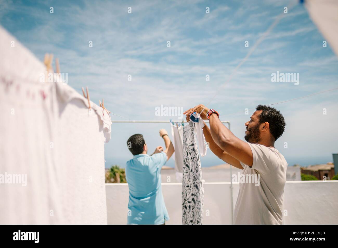 Multiracial men hanging clothes in bright day Stock Photo - Alamy