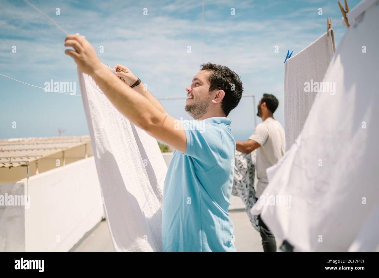 Multiracial men hanging clothes in bright day Stock Photo - Alamy