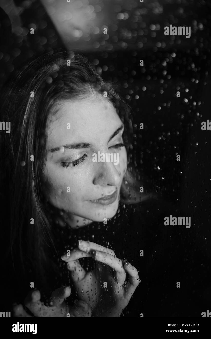 Black And White Of Smiling Woman Standing Behind Glass In Water Drops