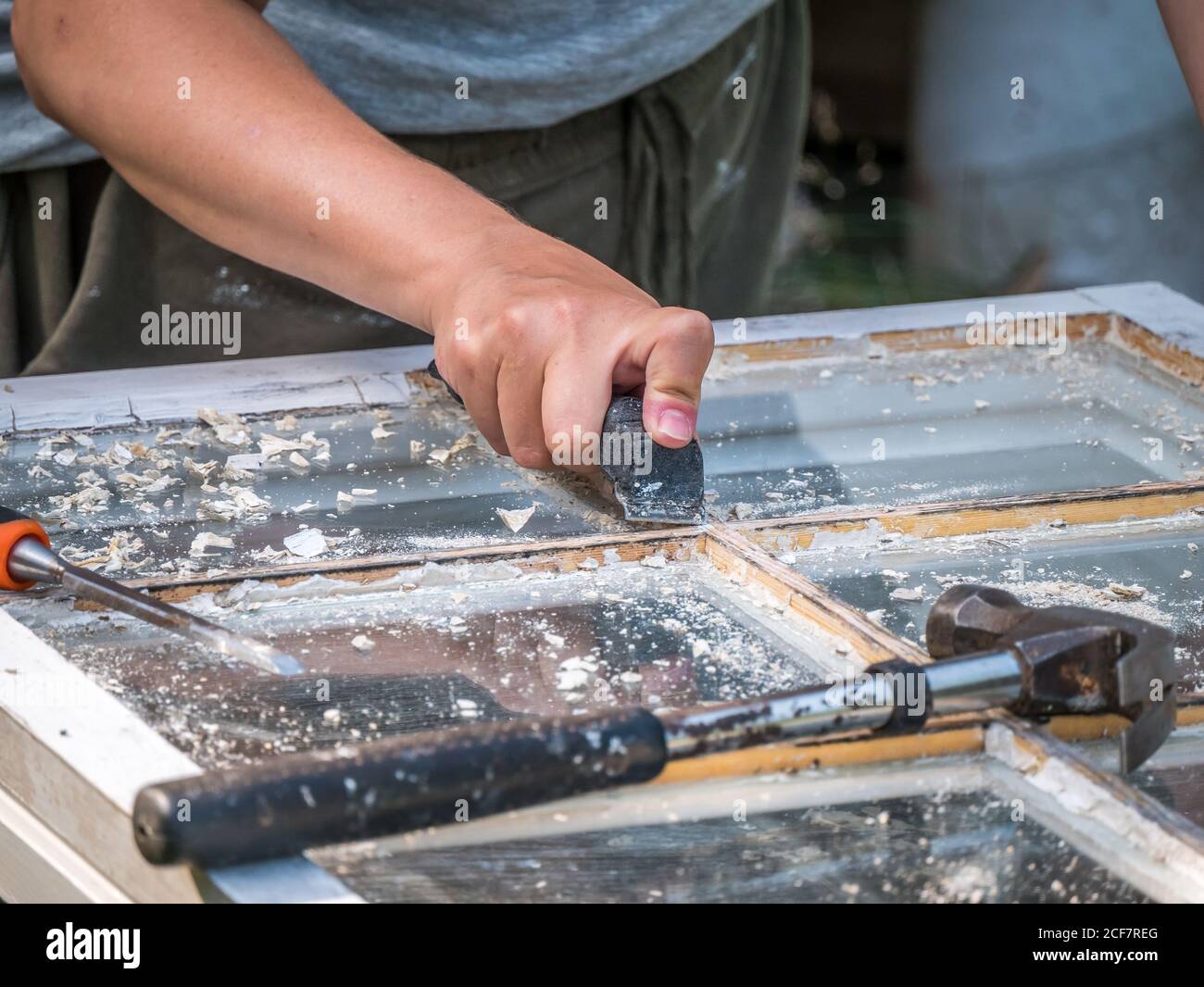Woman is doing a window recondition by scraping old color to fix window ...