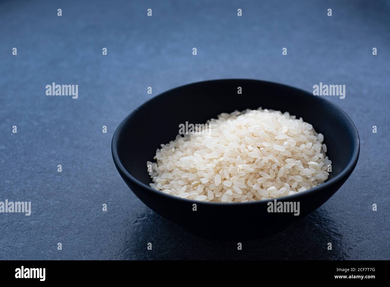 Uncooked rice grains in bowl on dark background with copy space Stock ...