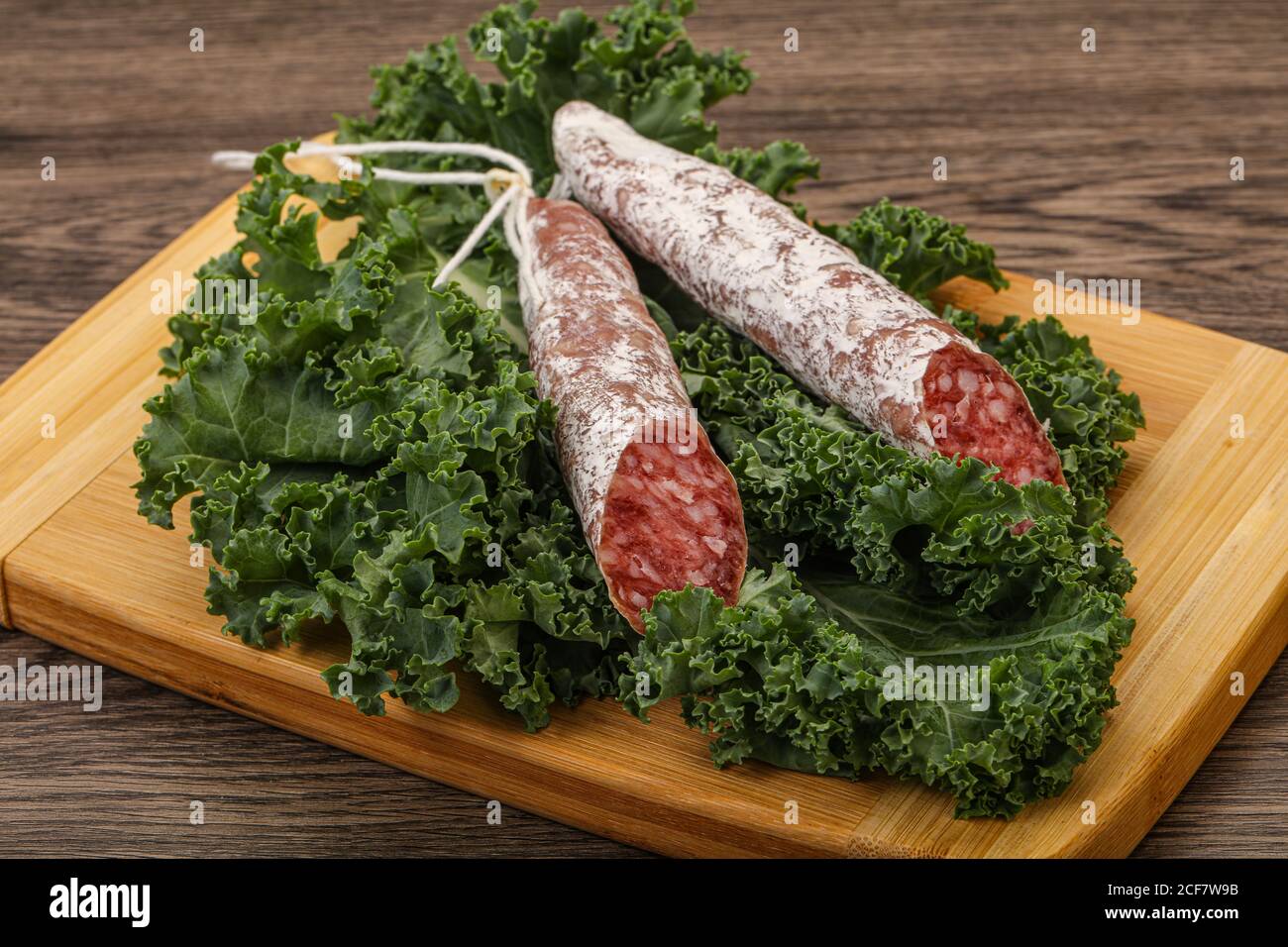 Spanish Fuet sausage with salad leaves over wooden background Stock ...