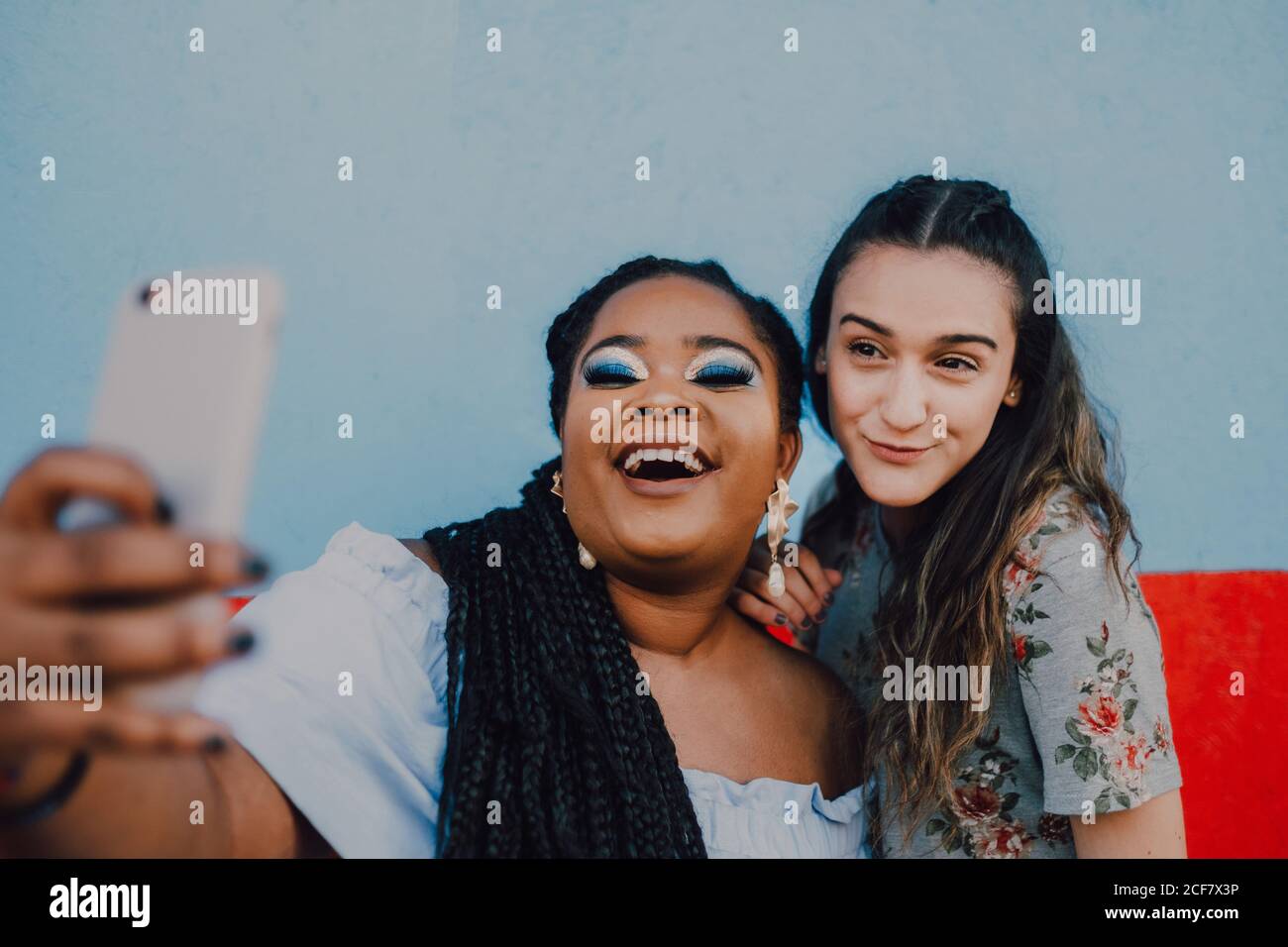Playful multiracial young casual women laughing and taking selfie with ...