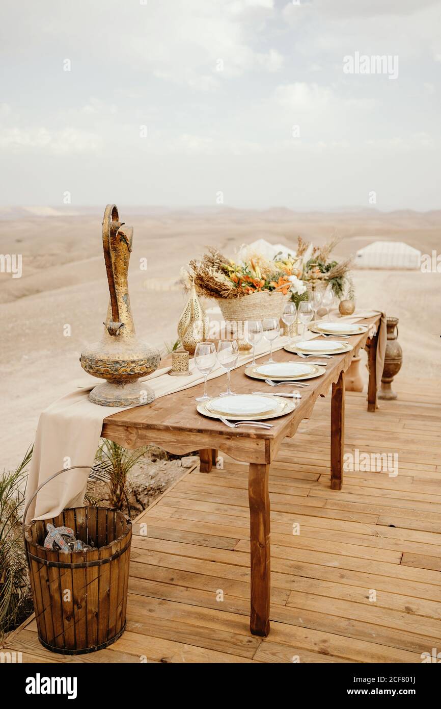 Long wooden table decorated with flowers and candles and served with ...