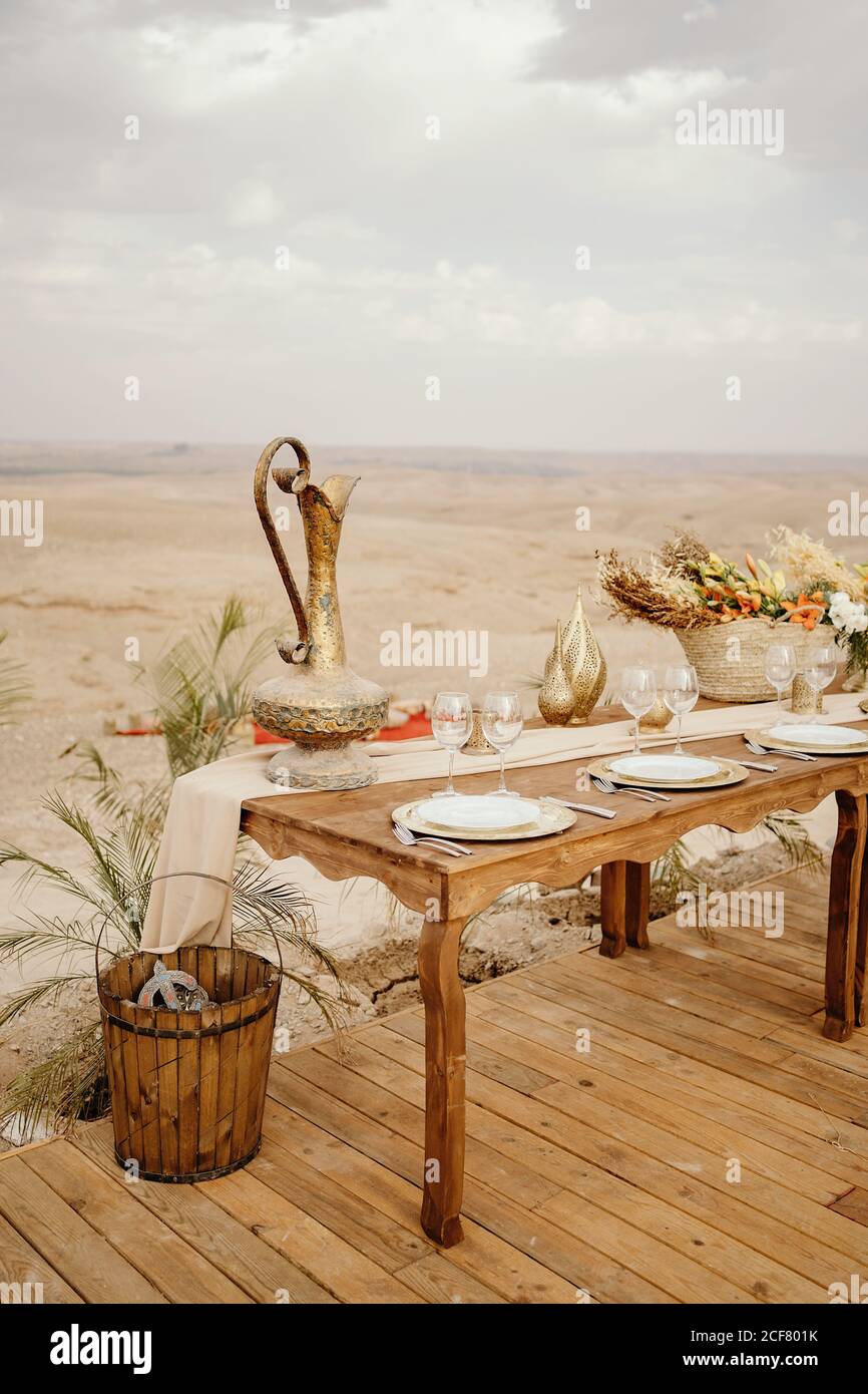 Long wooden table decorated with flowers and candles and served with ...