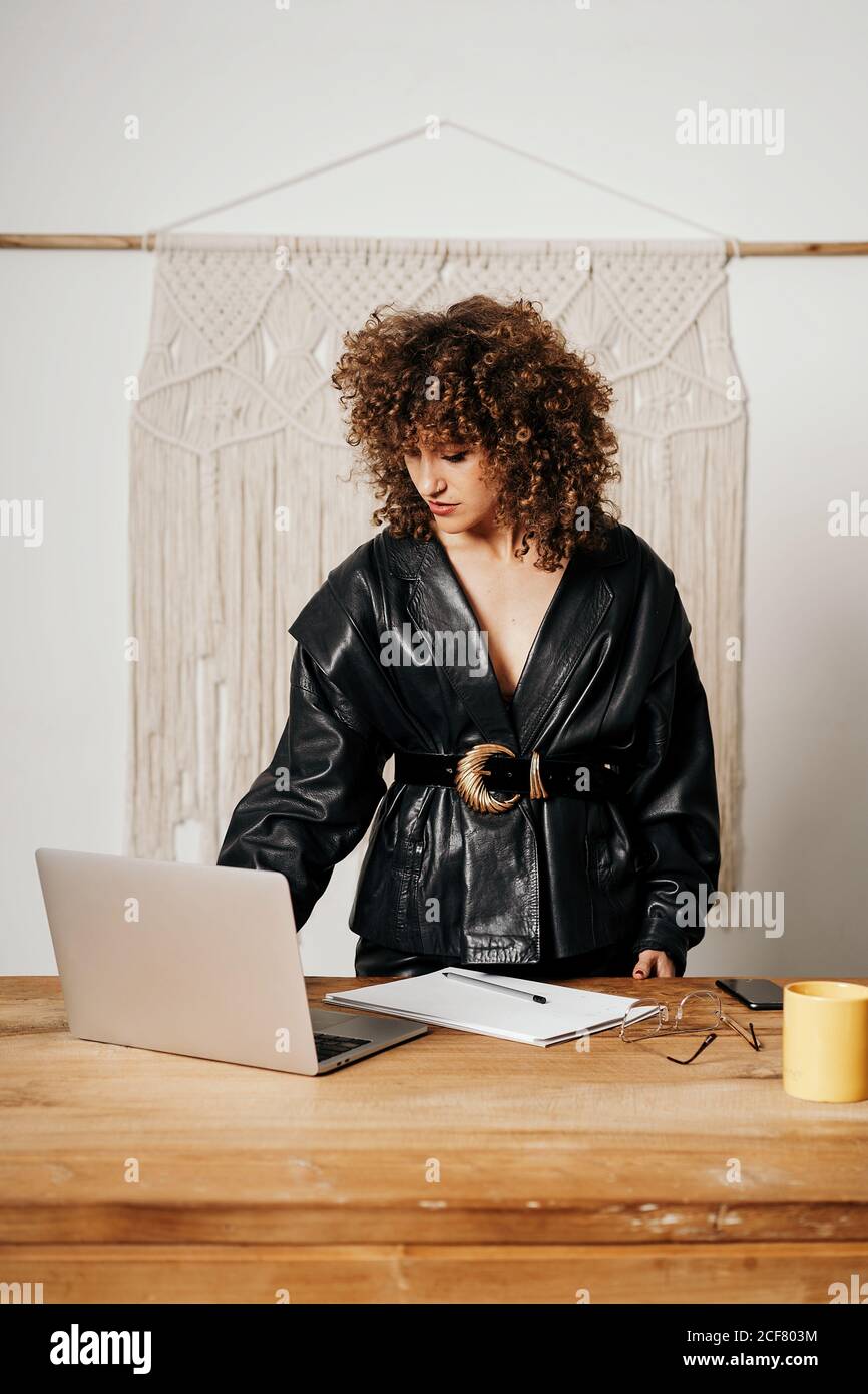 Full body female entrepreneur in retro outfit browsing laptop during ...