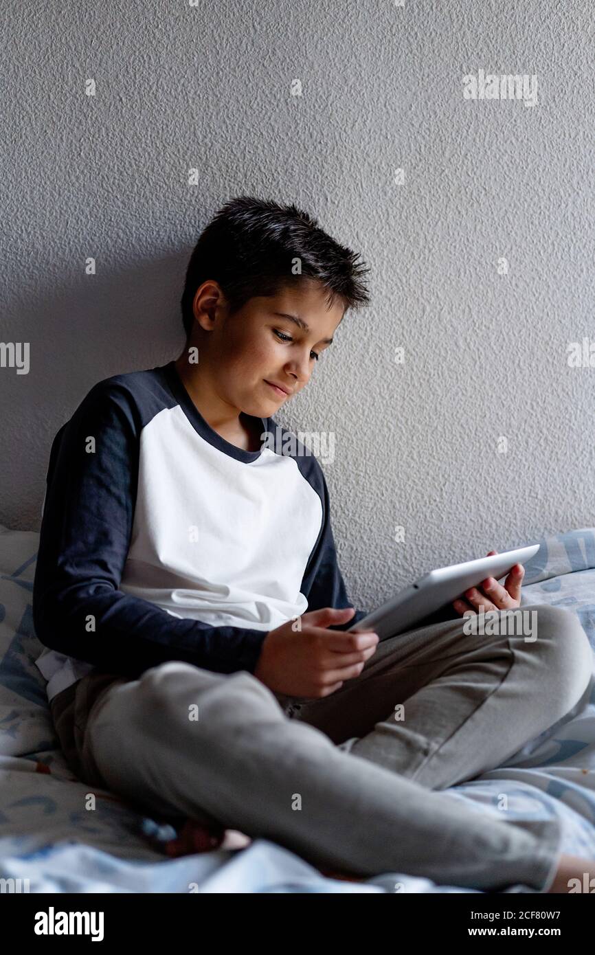 Delighted boy using tablet in bedroom during weekend Stock Photo - Alamy