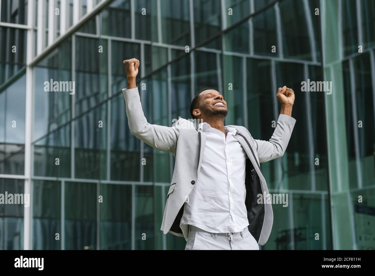 Enthusiastic black man rejoicing raising hands up Stock Photo - Alamy