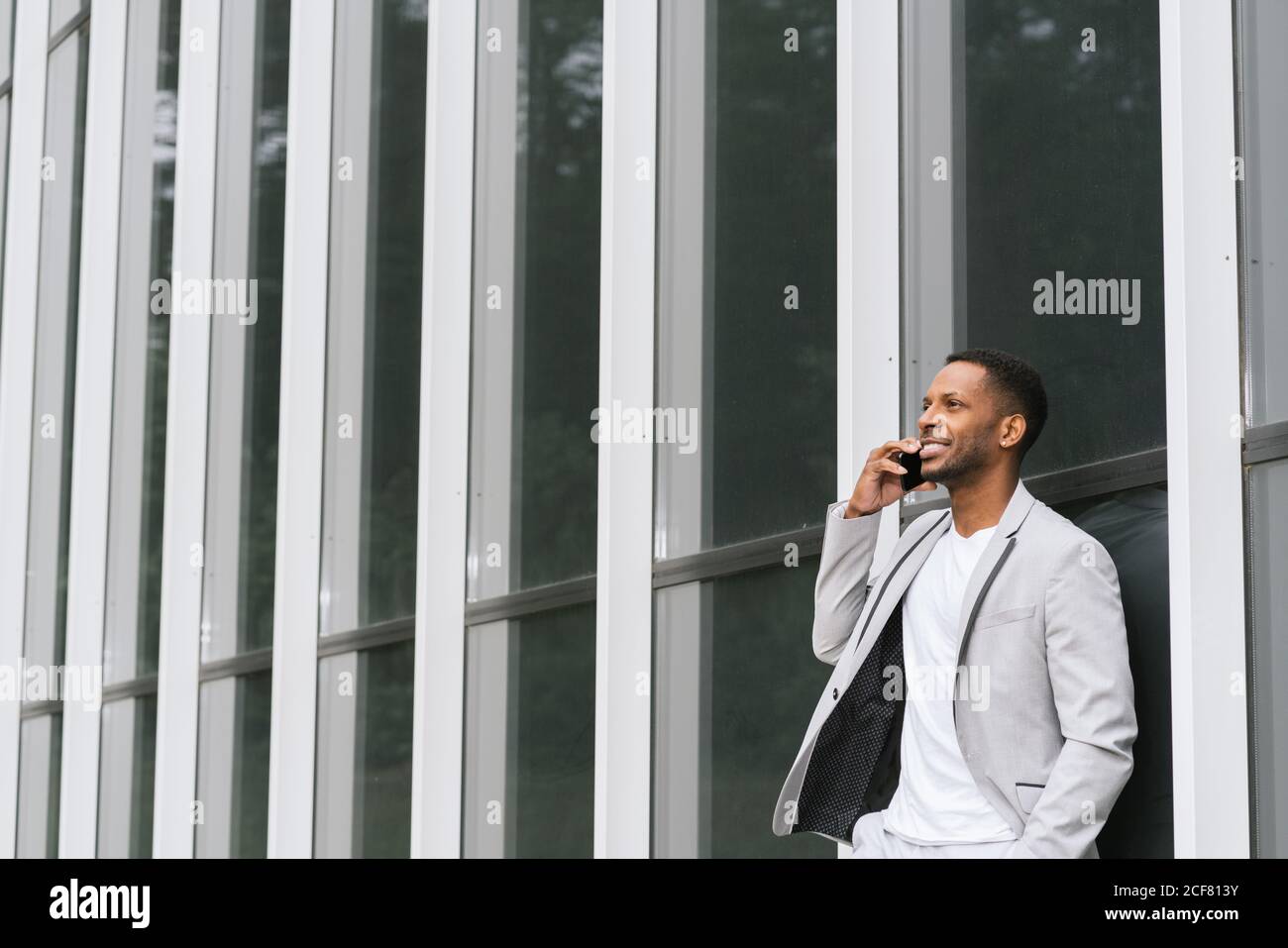 Elegant black man talking smartphone leaning building Stock Photo - Alamy