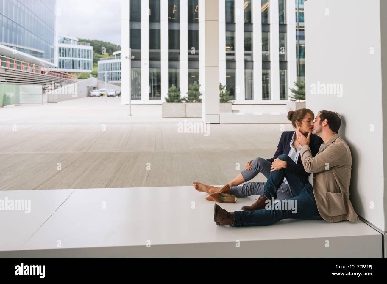 Male manager hugging and kissing girlfriend while sitting outside ...