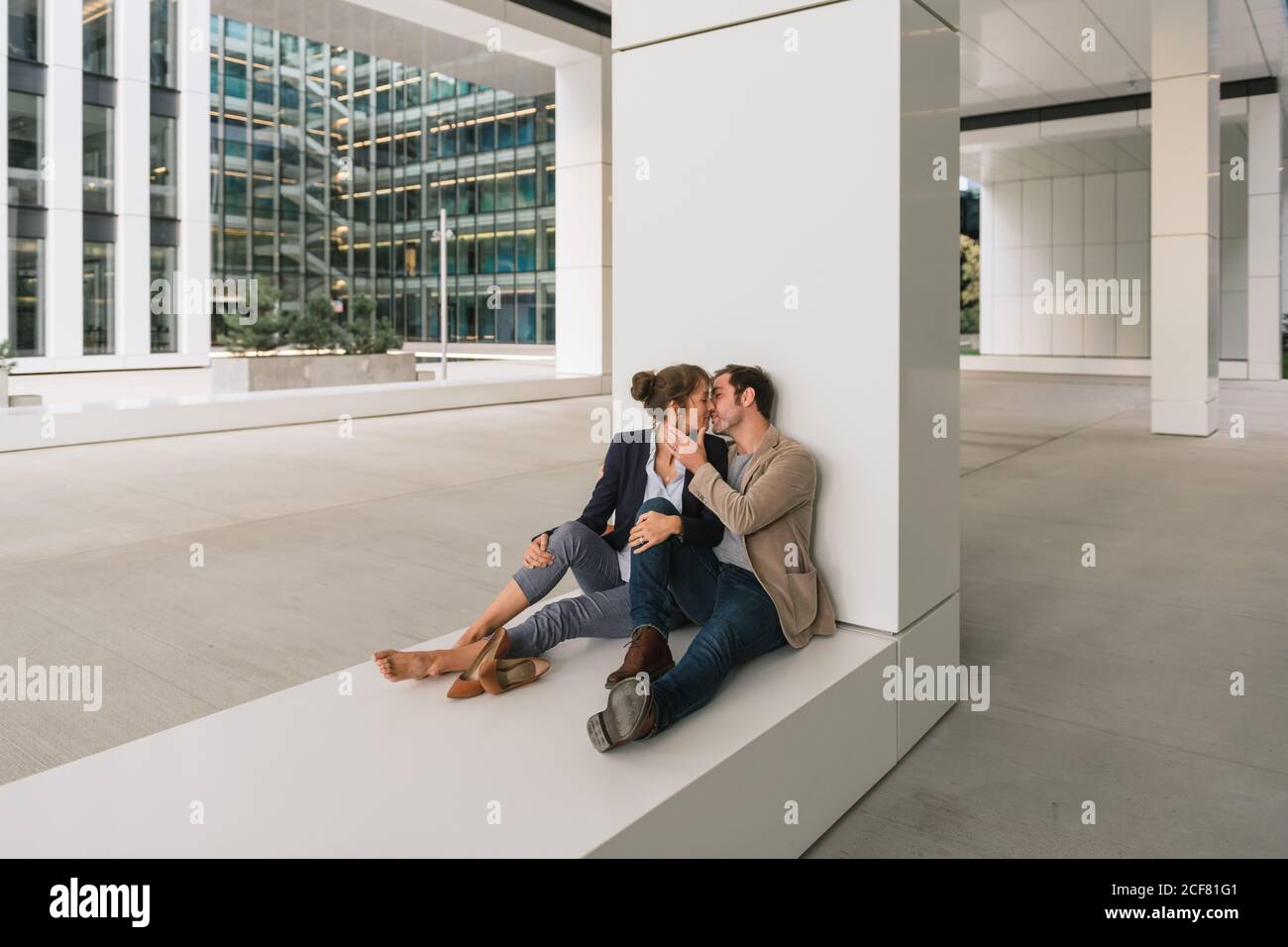 Male manager hugging and kissing girlfriend while sitting outside ...