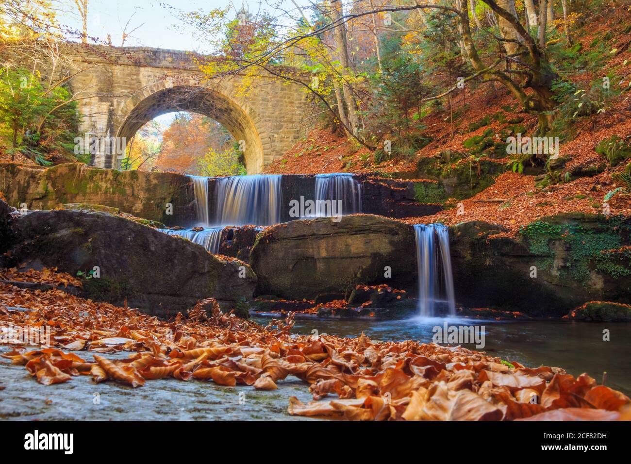 Autumn waterfall under stone bridge in the mountain Stock Photo - Alamy