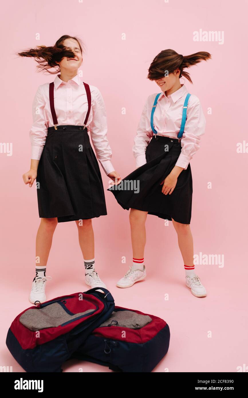 Happy little twin schoolgirls with twintails shaking heads. Low angle ...