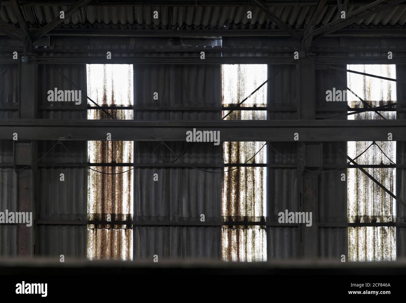 Shabby old rust metal wall with highlights of penetrating light from ...