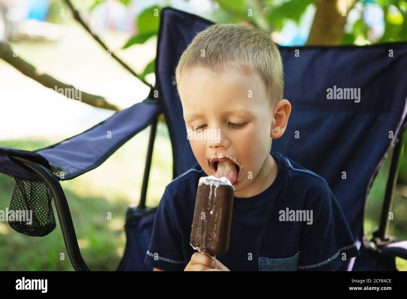 Adorable little boy eating ice cream pops in home's garden, outdoors ...