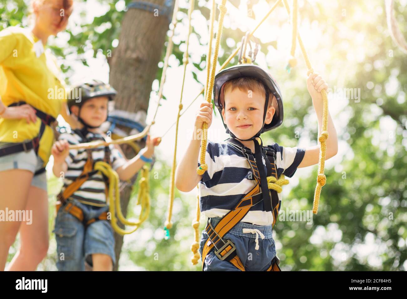 Kids climbing in adventure park. Boy enjoys climbing in the ropes ...