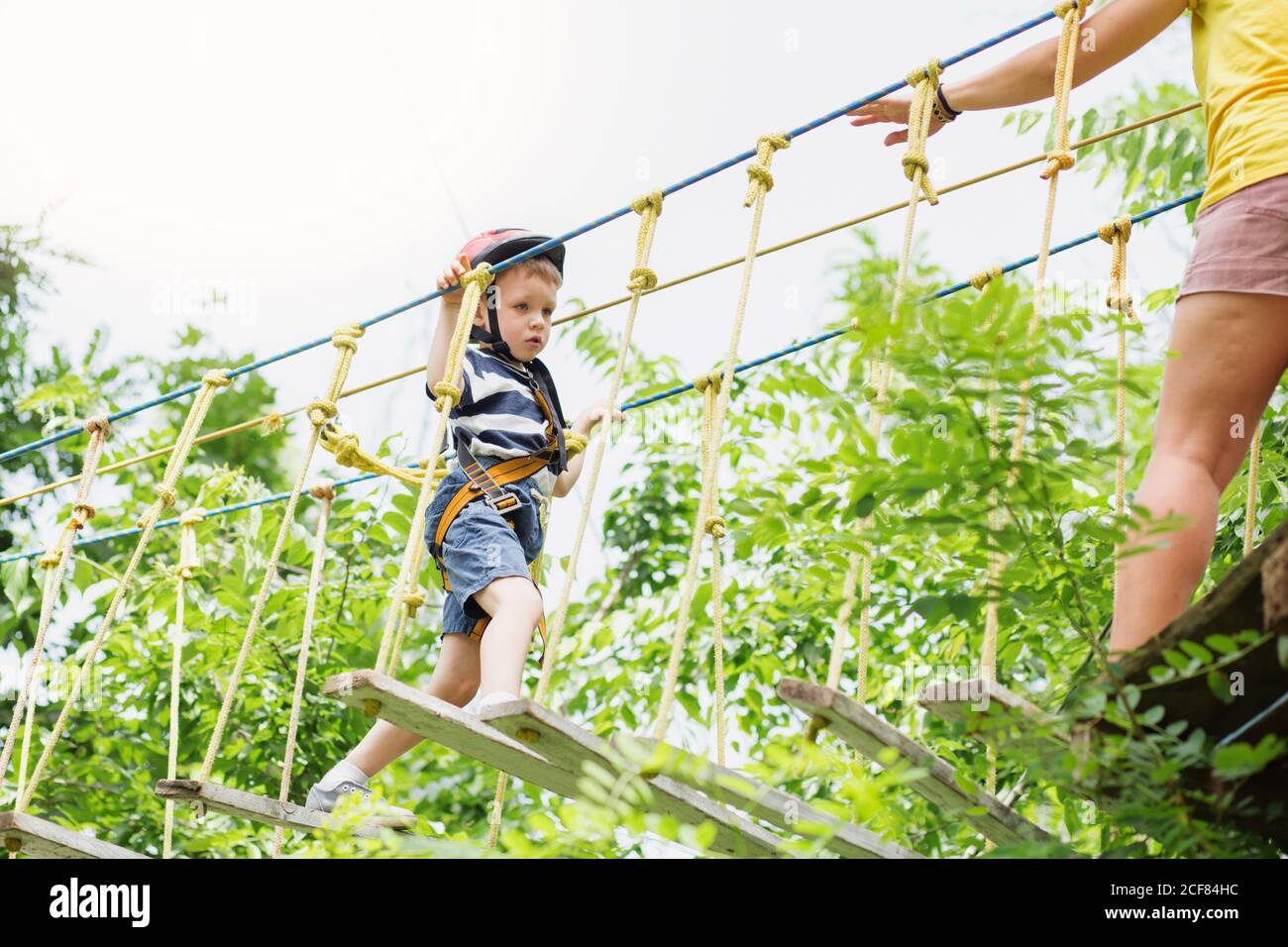 Kids climbing in adventure park. Boy enjoys climbing in the ropes ...