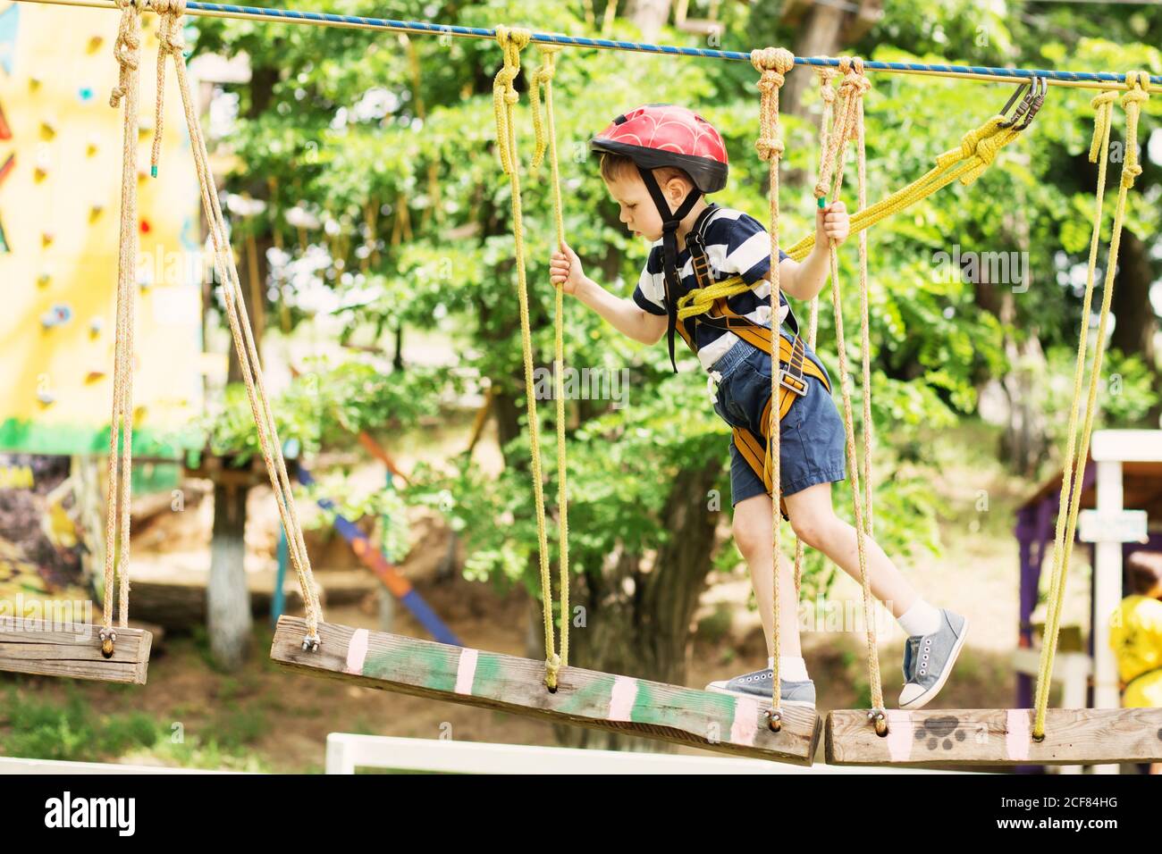 Kids climbing in adventure park. Boy enjoys climbing in the ropes ...